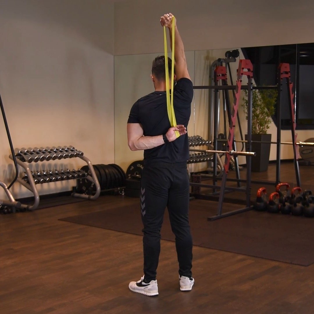 Prostowanie ramienia nad głową na triceps z gumą mini band stojąc